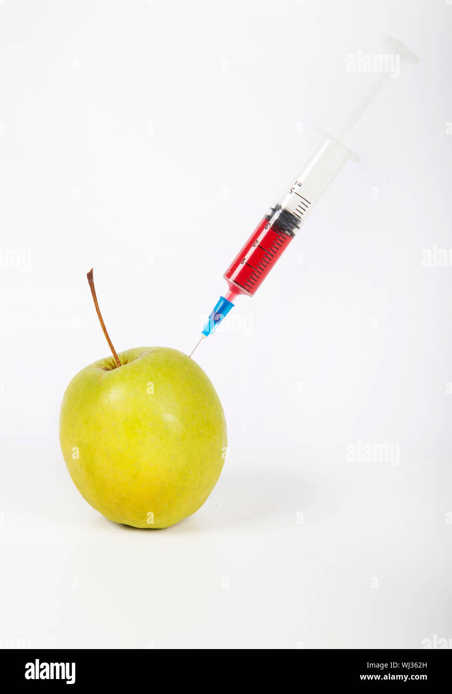 Granny smith apple being injected over white background Stock Photo - Alamy