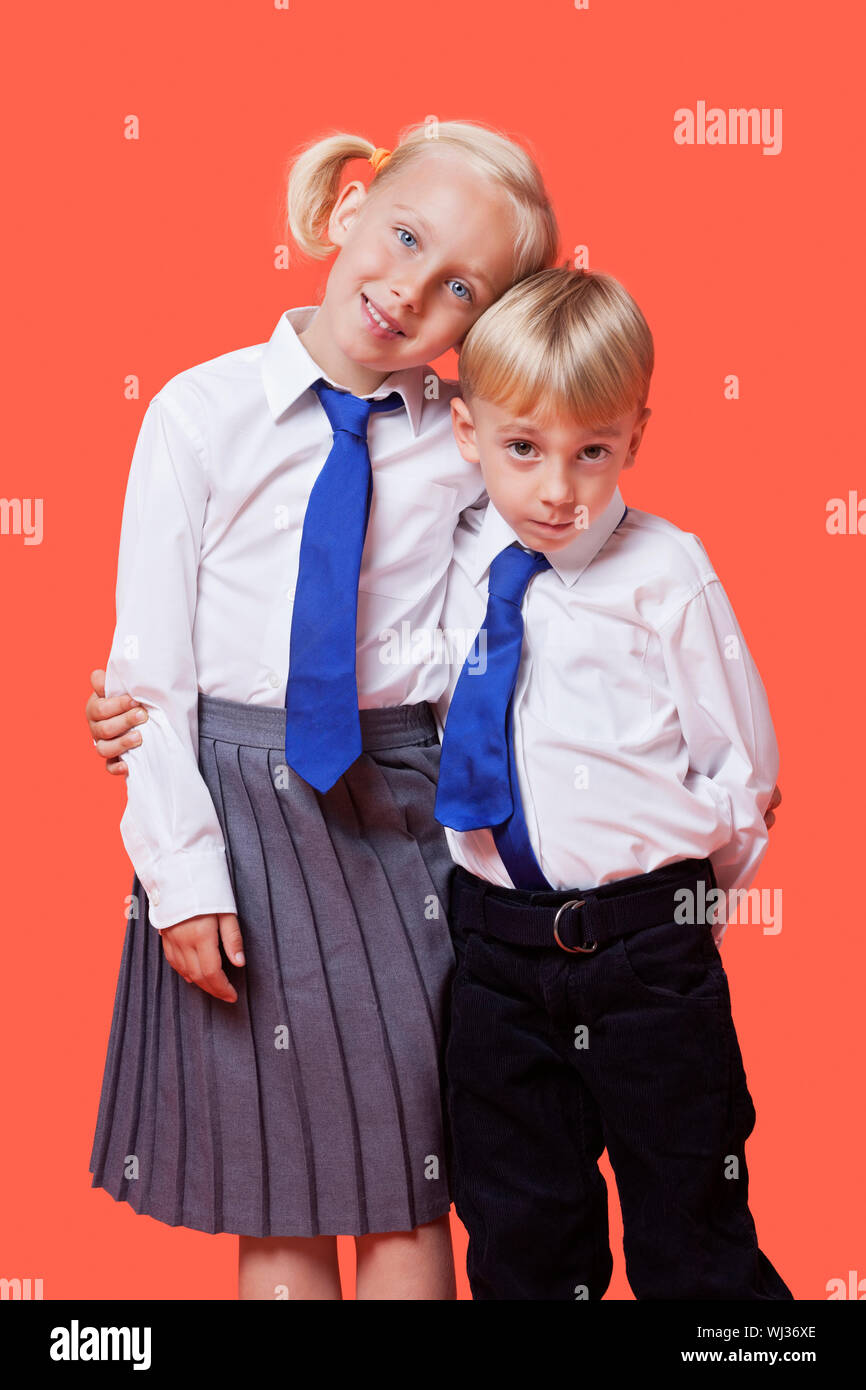 Portrait of young siblings in school uniform with arm around over ...