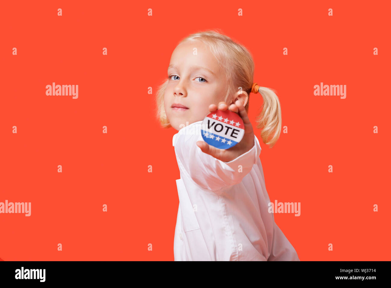 Portrait of a young girl showing vote badge over pink background Stock ...