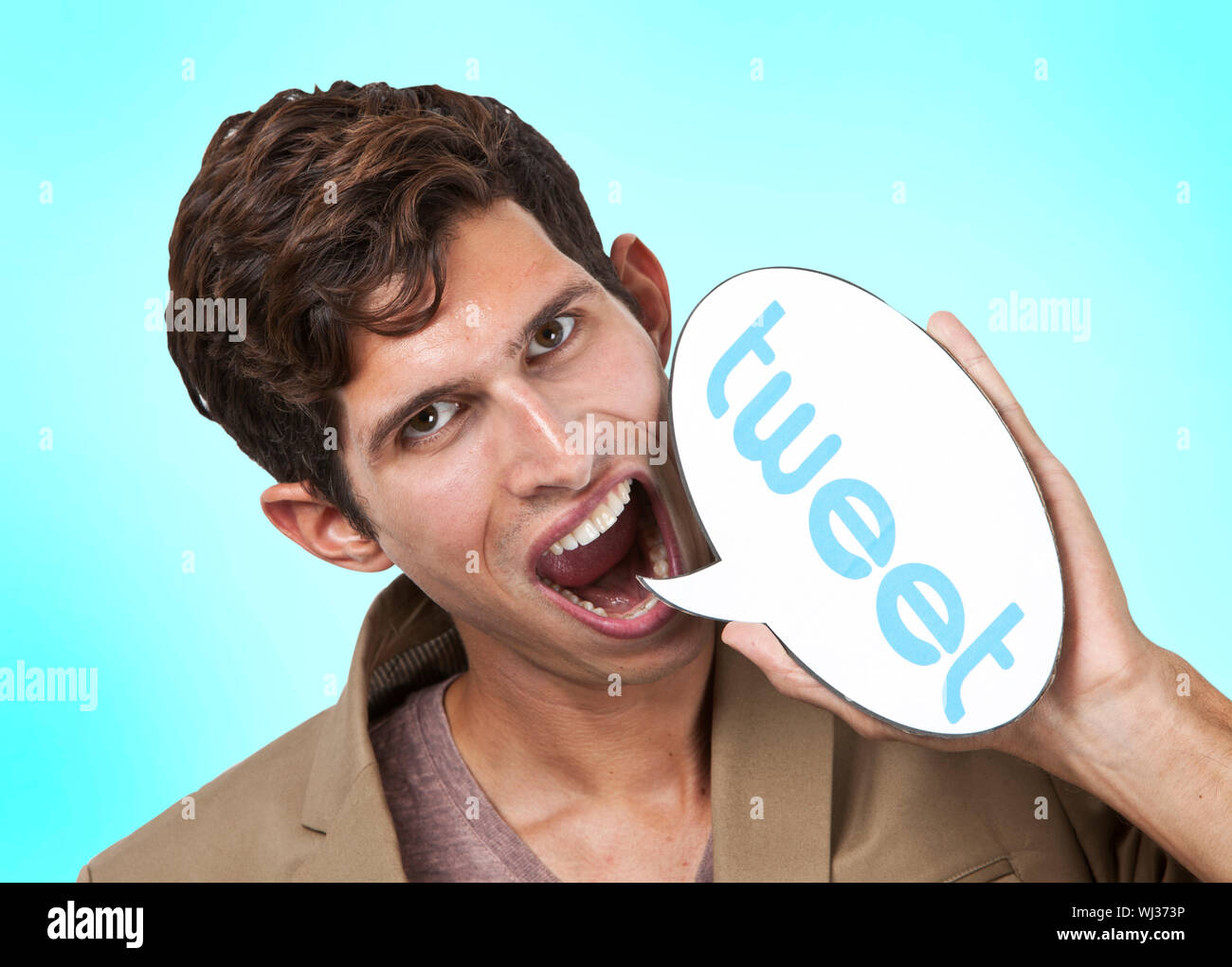 Portrait of young man holding tweet word bubble against white ...
