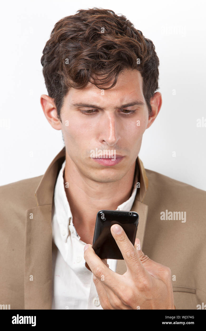 Pensive young man reading text message against white background Stock ...