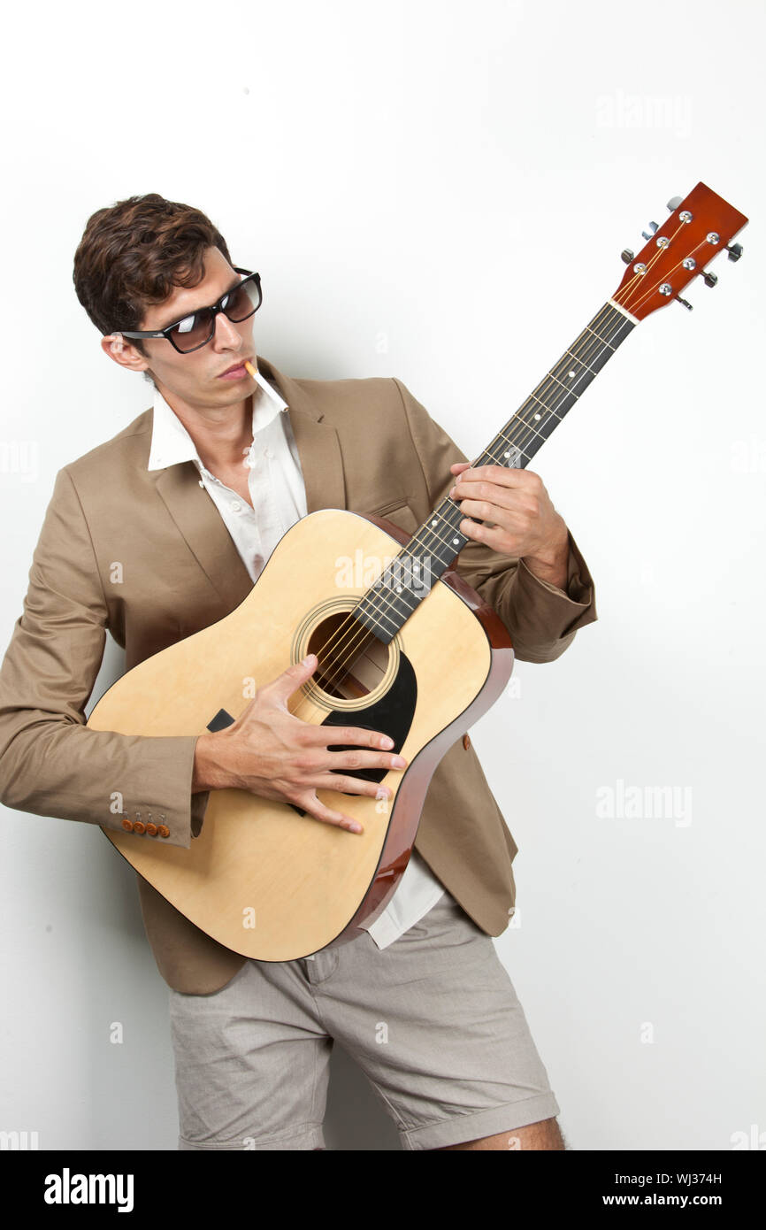 Young man smoking while playing guitar against white background Stock ...
