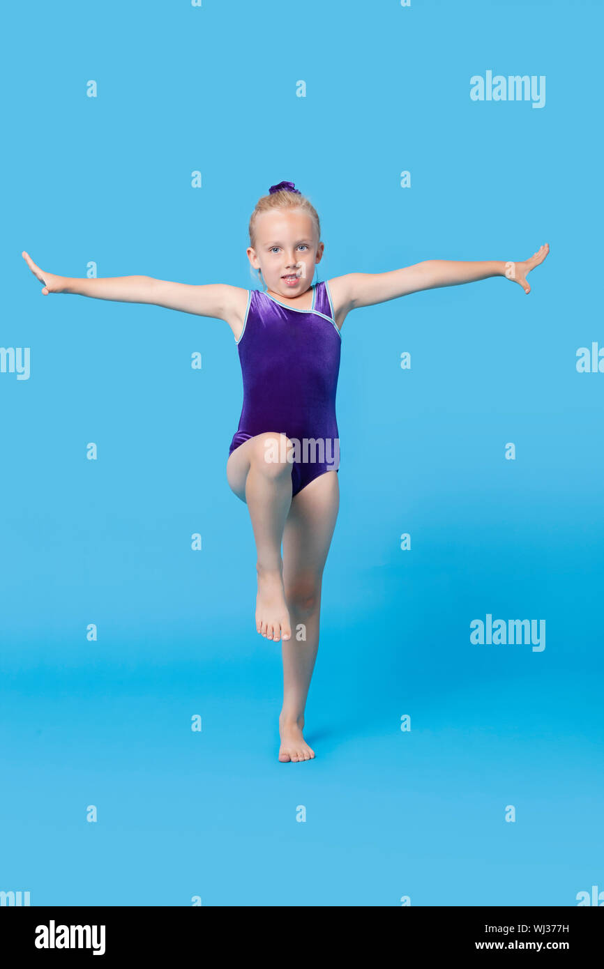 Portrait of a young female gymnast performing over blue background ...