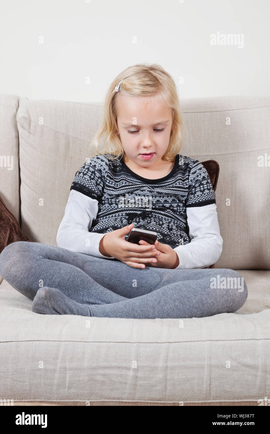 Young girl reading text message on sofa Stock Photo - Alamy