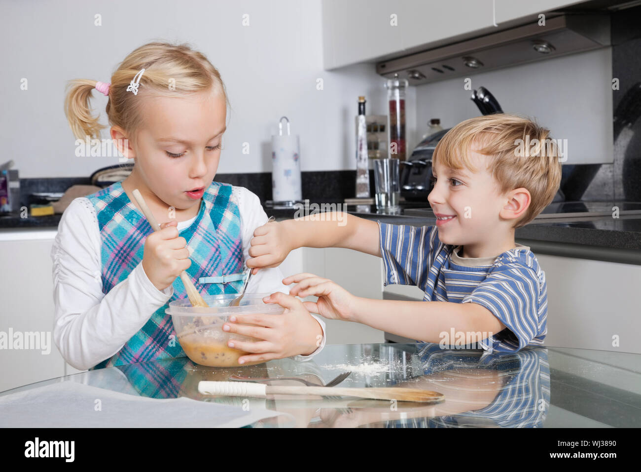 Happy brother and sister mixing batter together in kitchen Stock Photo ...