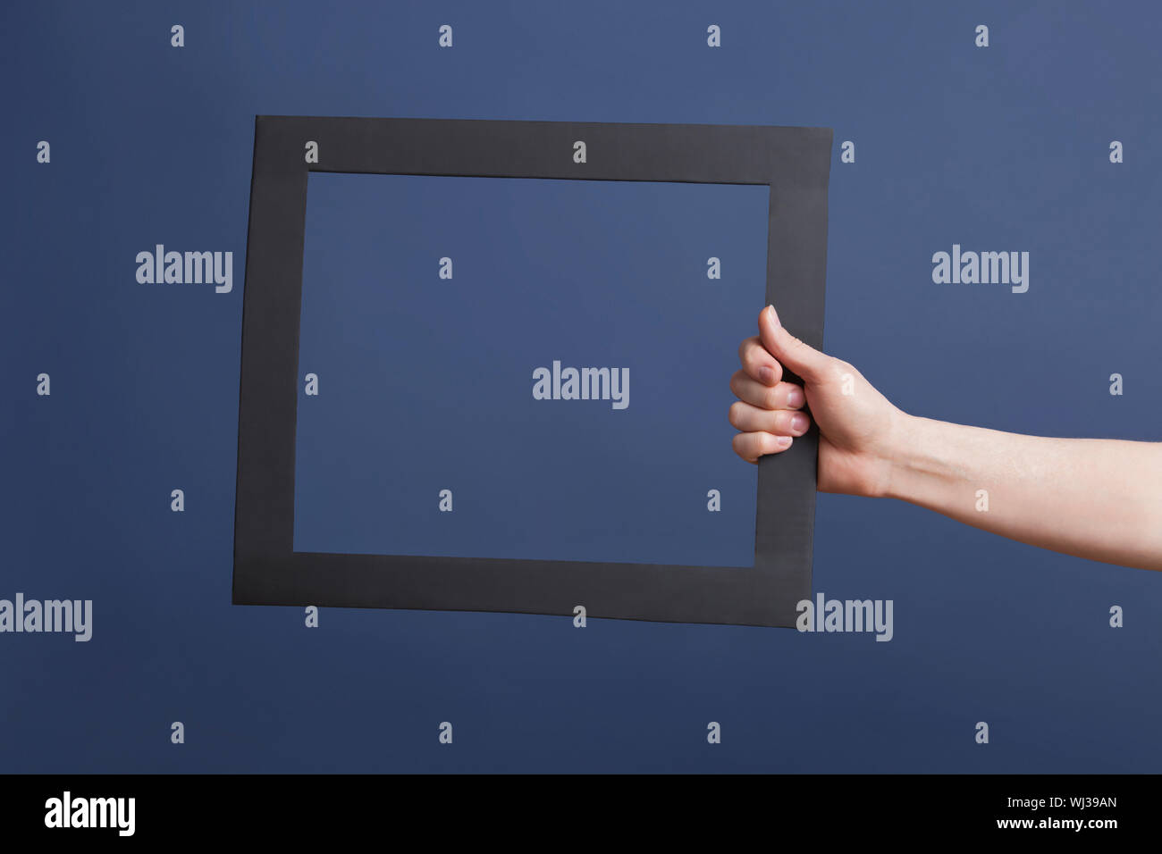 Hand holding frame over blue background Stock Photo - Alamy