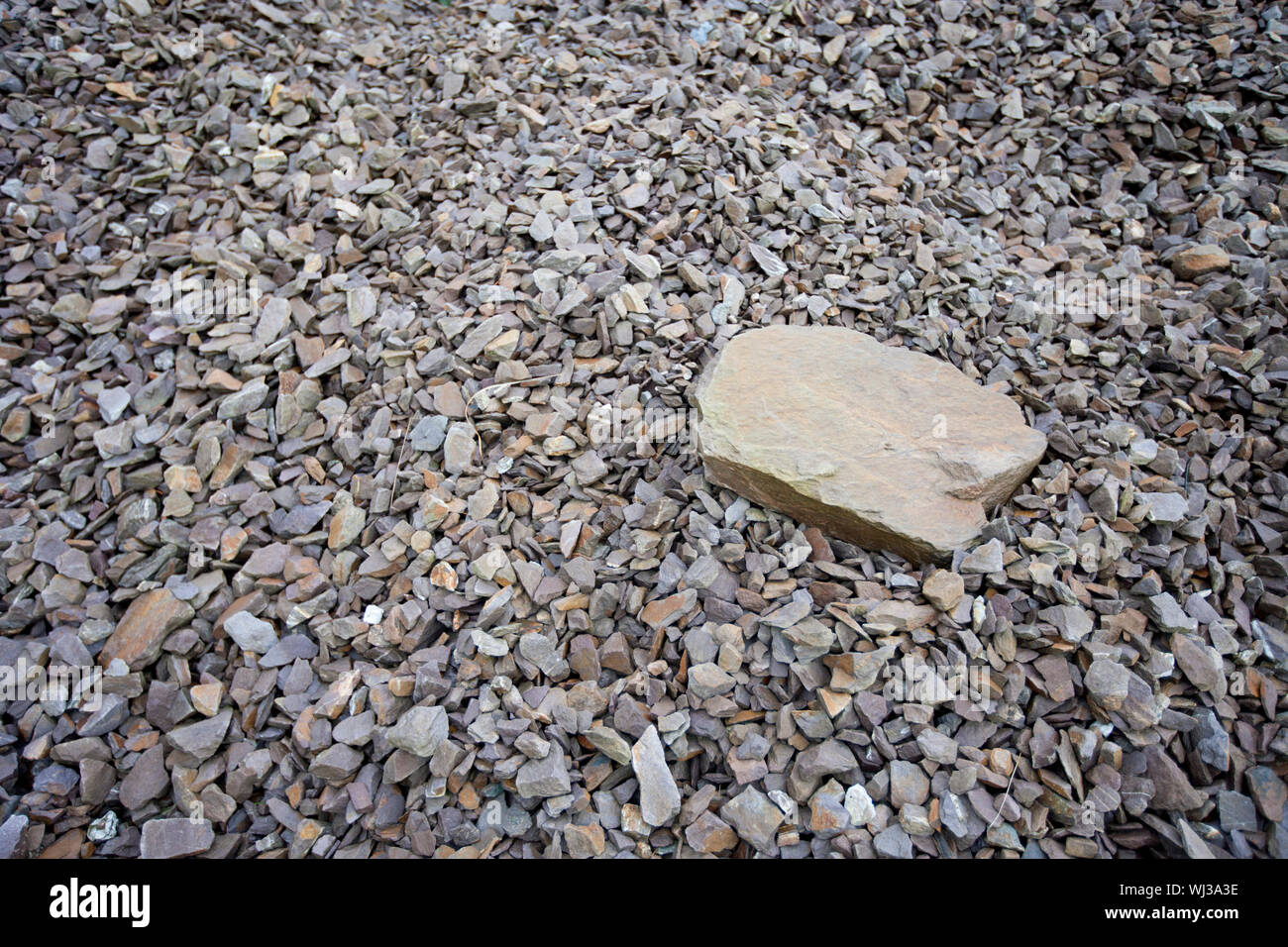 Large rock sitting on pile of smaller rocks Stock Photo - Alamy