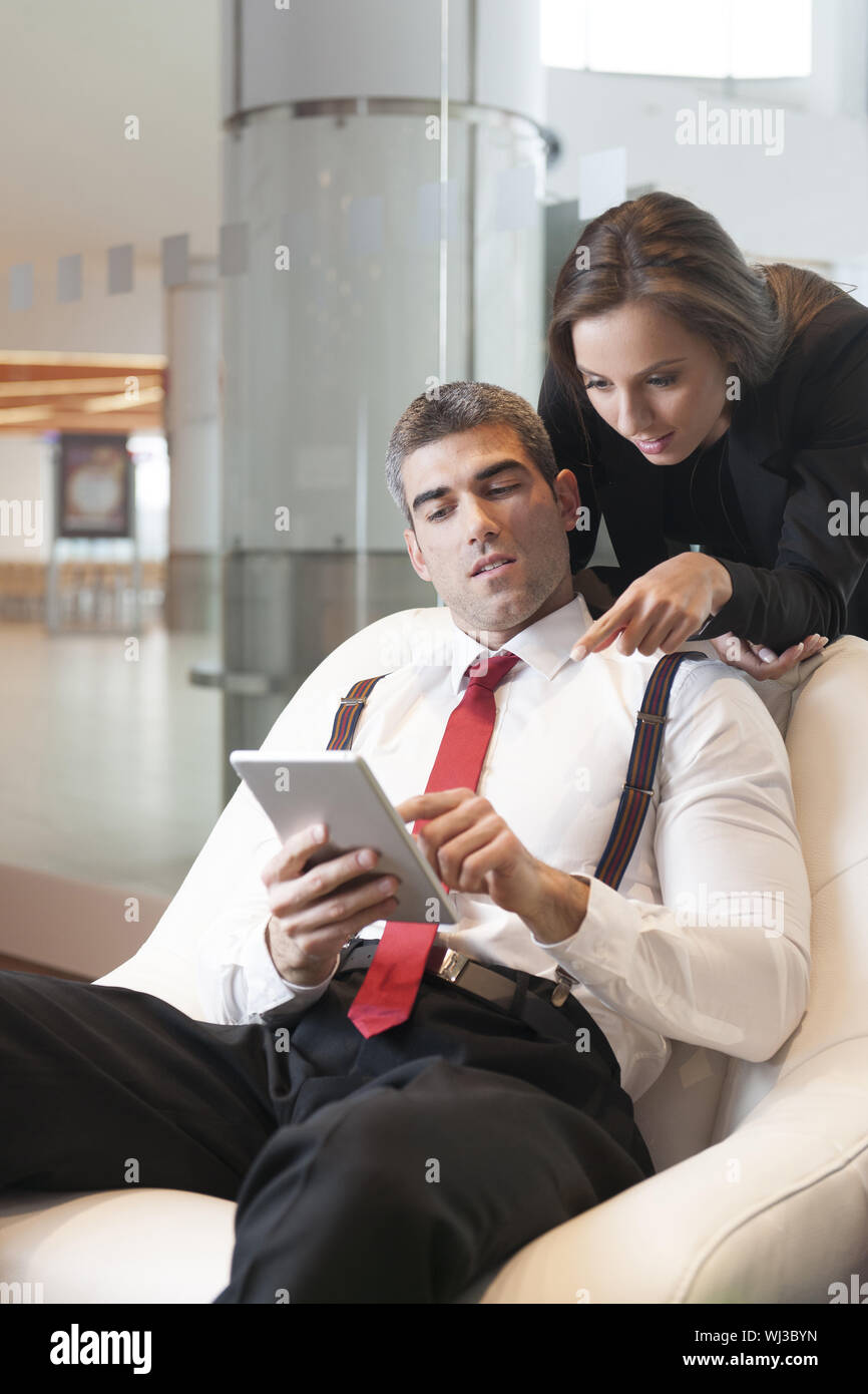 Businesswoman looking over male colleagues shoulder pointing at digital ...