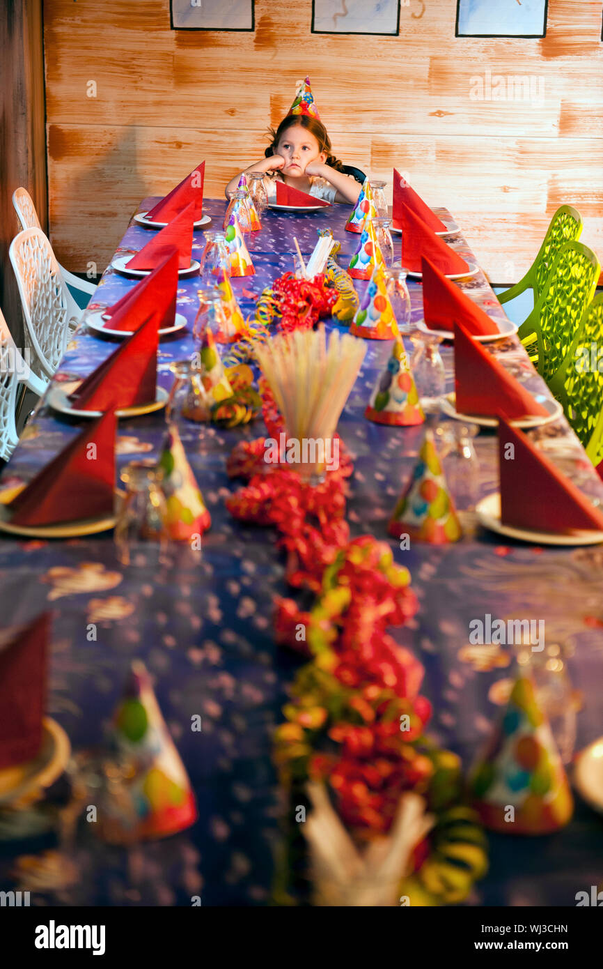 Bored young girl at head of fully set but empty birthday table Stock ...