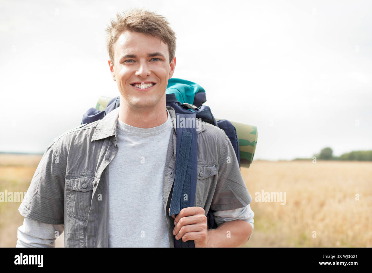 Portrait of handsome male hiker with backpack standing on field Stock ...
