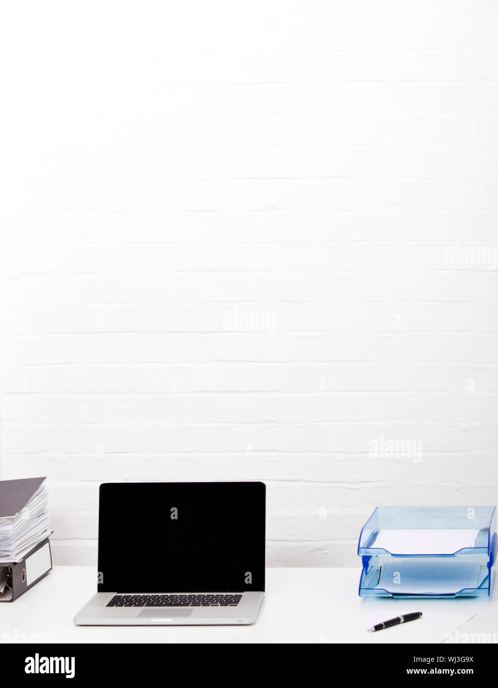 Laptop and paper tray on office desk Stock Photo - Alamy