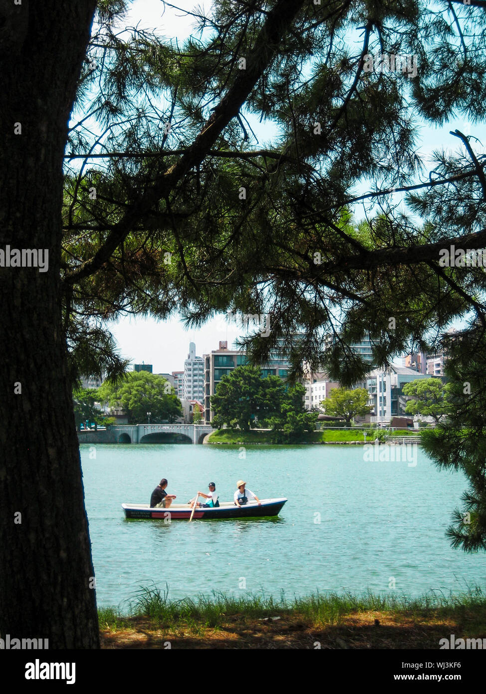 people riding small boat in large body of water in fukuoka japan ...