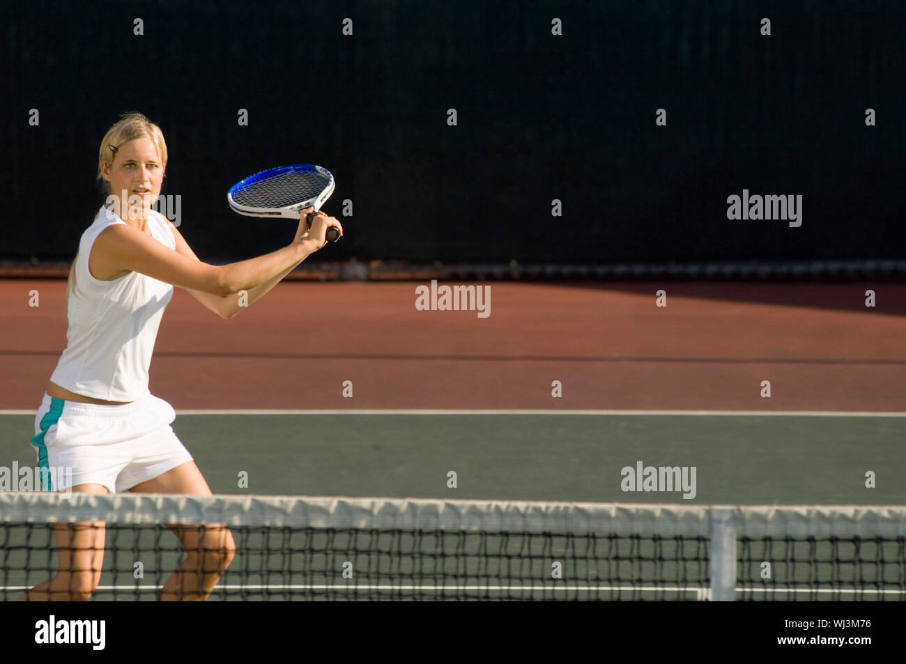 Young female tennis player swinging racket at court Stock Photo - Alamy