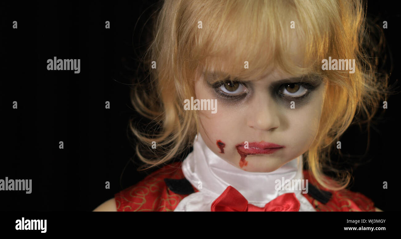 Dracula child. Little girl with halloween make-up making faces. Vampire ...