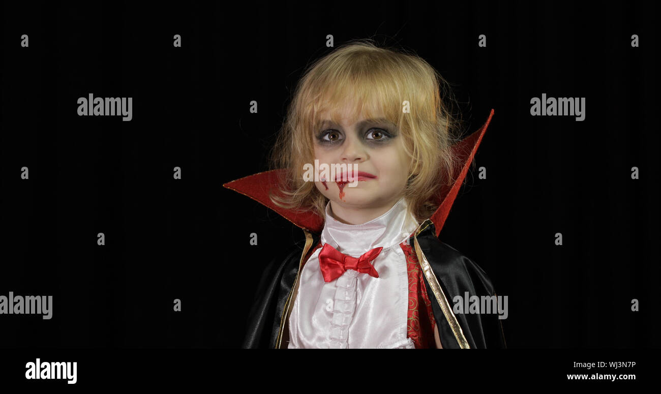 Dracula child. Little girl with halloween make-up making faces. Vampire ...