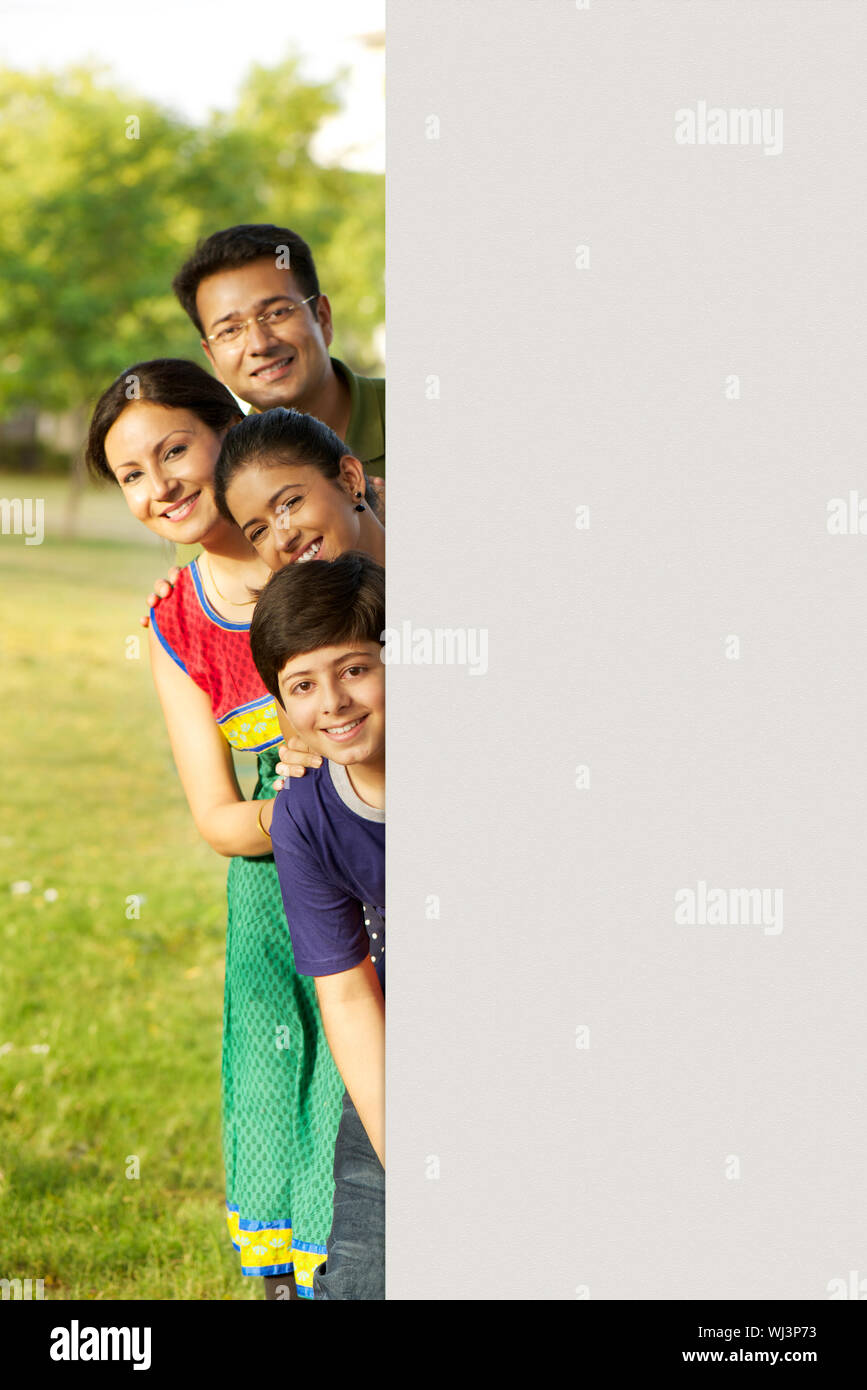 Family peeking out from behind placard Stock Photo - Alamy