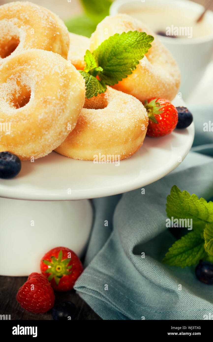 Coffee break with fresh berries and sugary donuts over white background ...