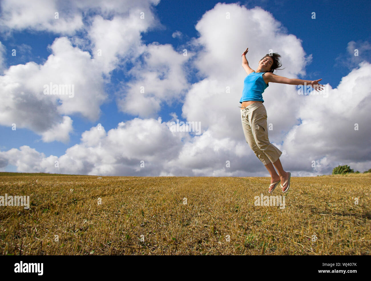Beautiful woman jumping on a golden meadow Stock Photo - Alamy