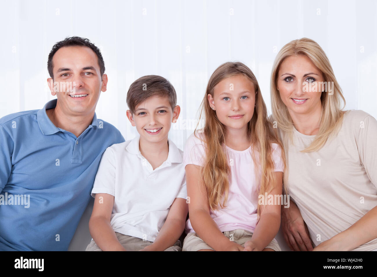 A Happy Family With Two Children Sitting On Sofa At Home Stock Photo ...