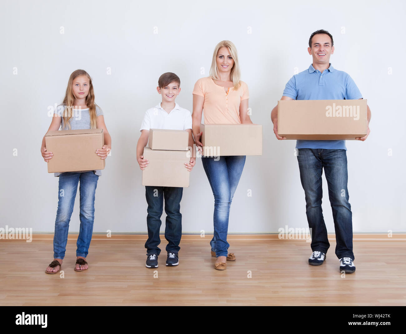Parents And Two Children With Cardboard Boxes, Indoors Stock Photo - Alamy