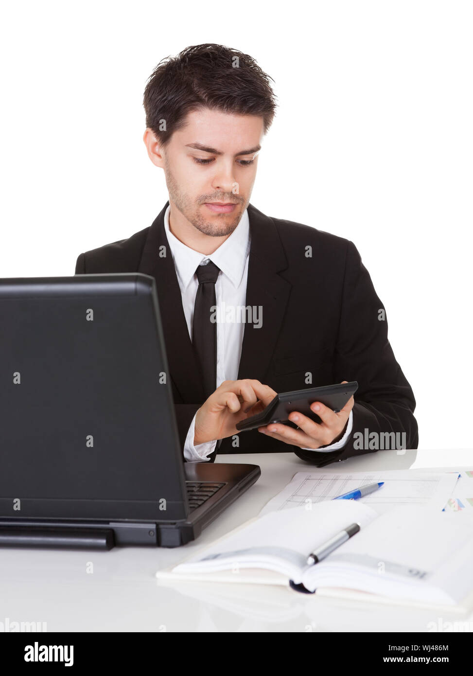 Smiling good looking young accountant sitting at his desk making ...