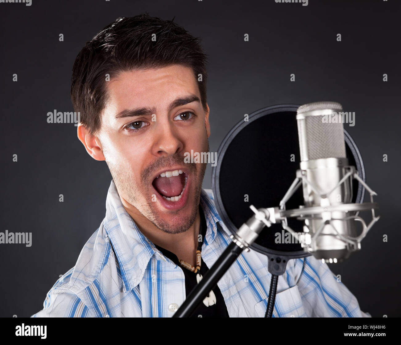 Portrait of young man singing into microphone Stock Photo - Alamy