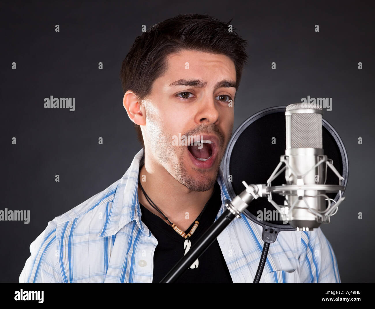 Portrait of young man singing into microphone Stock Photo - Alamy
