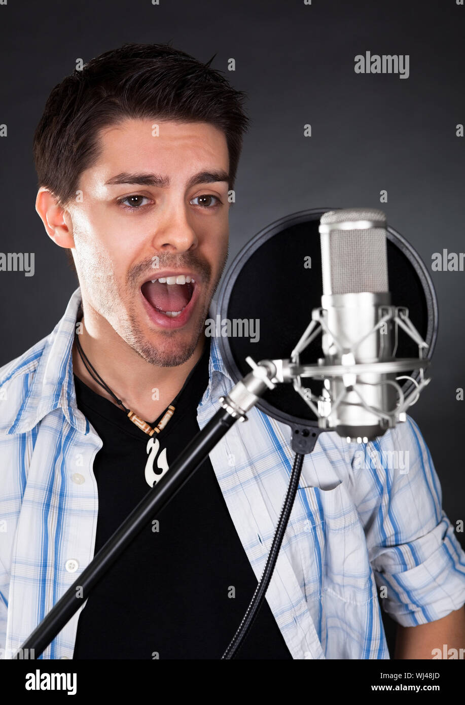 Portrait of young man singing into microphone Stock Photo - Alamy