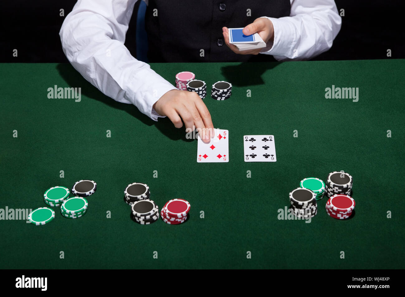 Croupier dealing cards in a poker game placing them face up on the ...