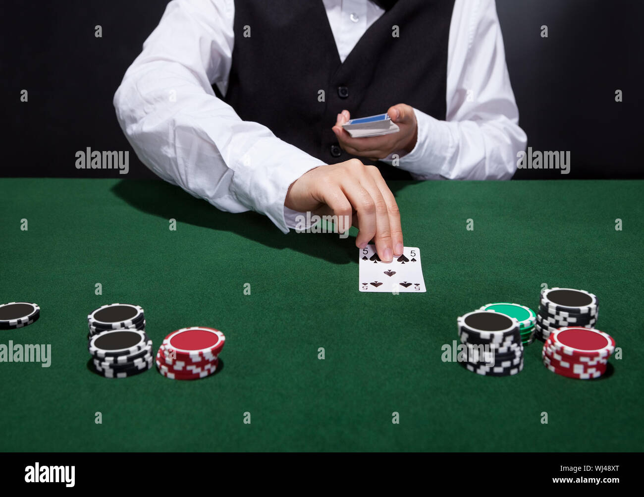 Croupier dealing cards in a poker game placing them face up on the ...