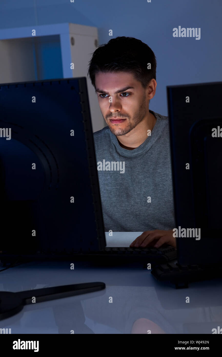 Man and two computers looking at screen in the dark Stock Photo - Alamy