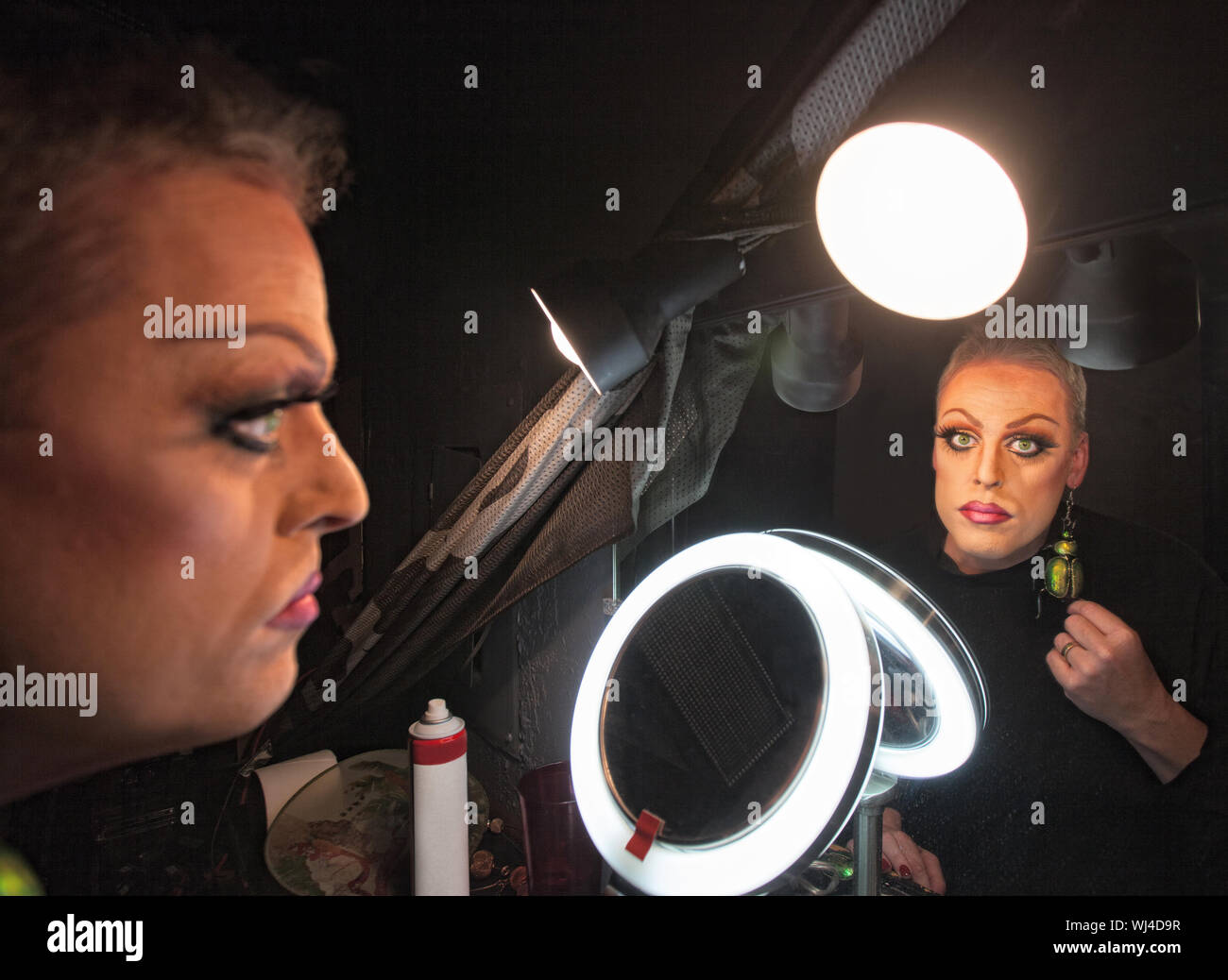 Serious drag queen in front of mirror with lamp Stock Photo - Alamy