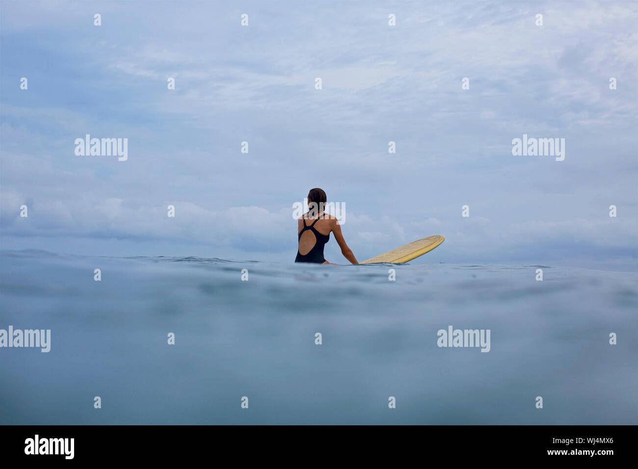 Female surfer straddling surfboard in ocean Stock Photo - Alamy