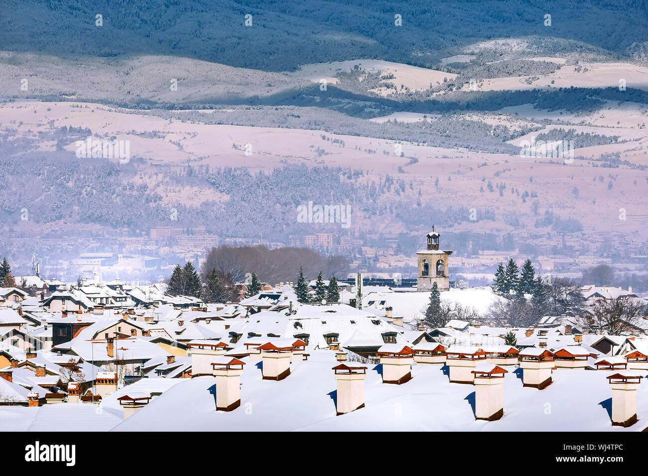 Bansko, Bulgaria aerial town winter view with houses snow roofs and St ...