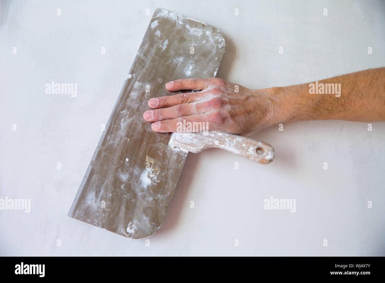 Plastering man hand with plaste and plaster spatula trowel in wall ...
