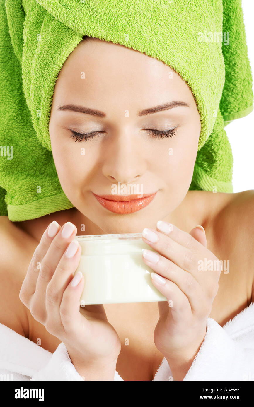 Beautiful woman in bathrobe and turban smelling body lotion. Isolated ...