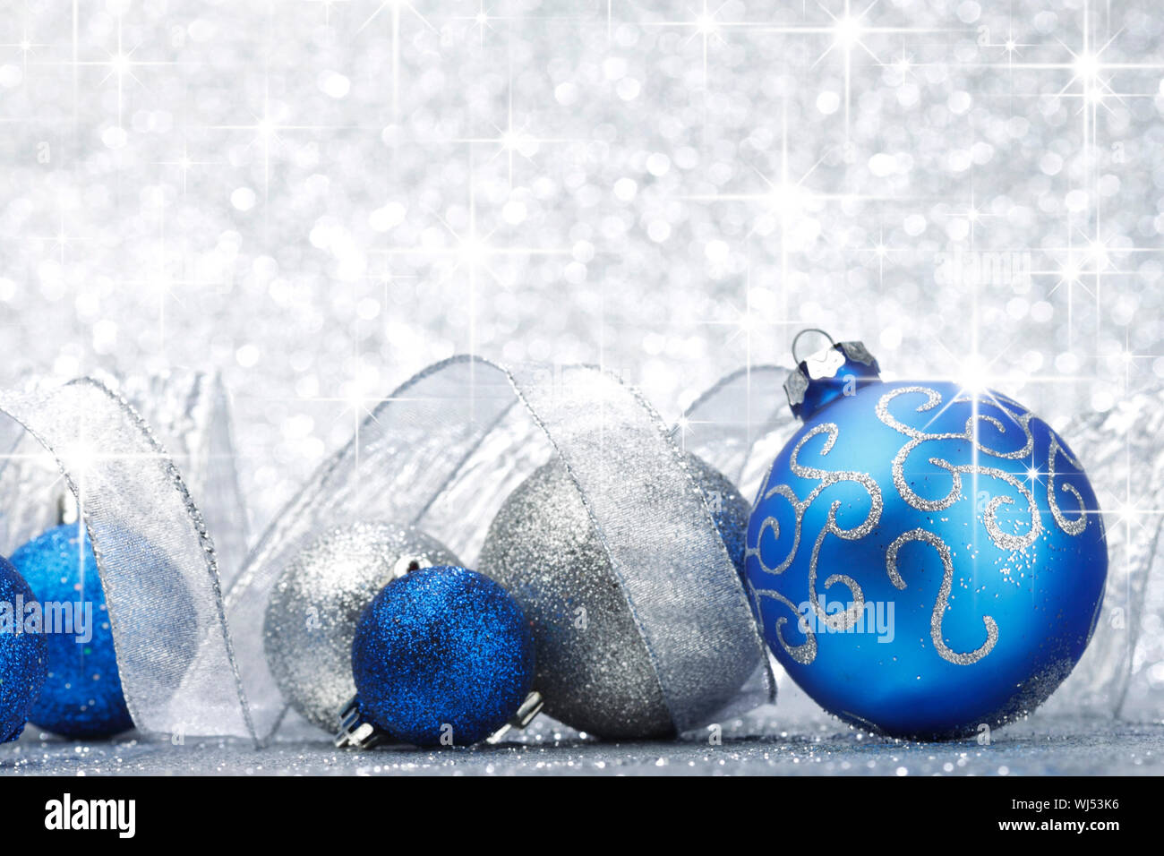 Blue shiny christmas balls and ribbon on silver glitter stars ...