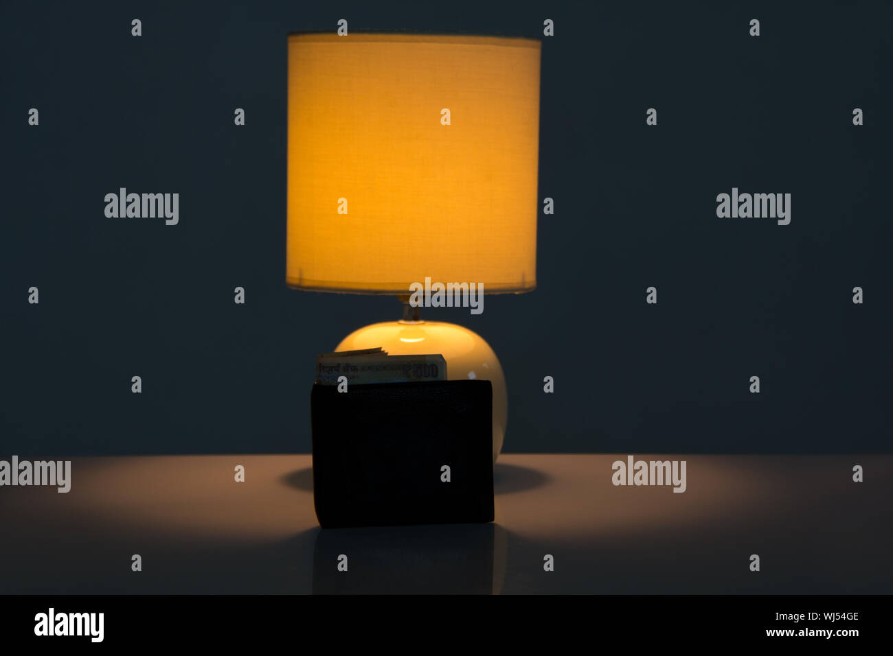 Glowing table lamp with wallet full of money Stock Photo - Alamy