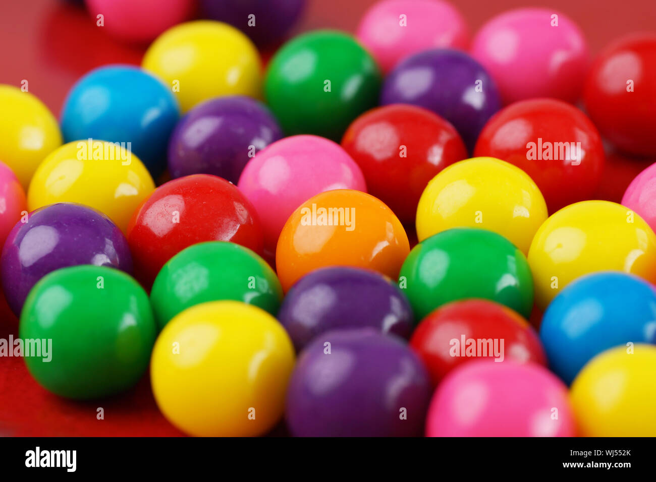 Colorful gumballs with only one orange in the middle Stock Photo - Alamy