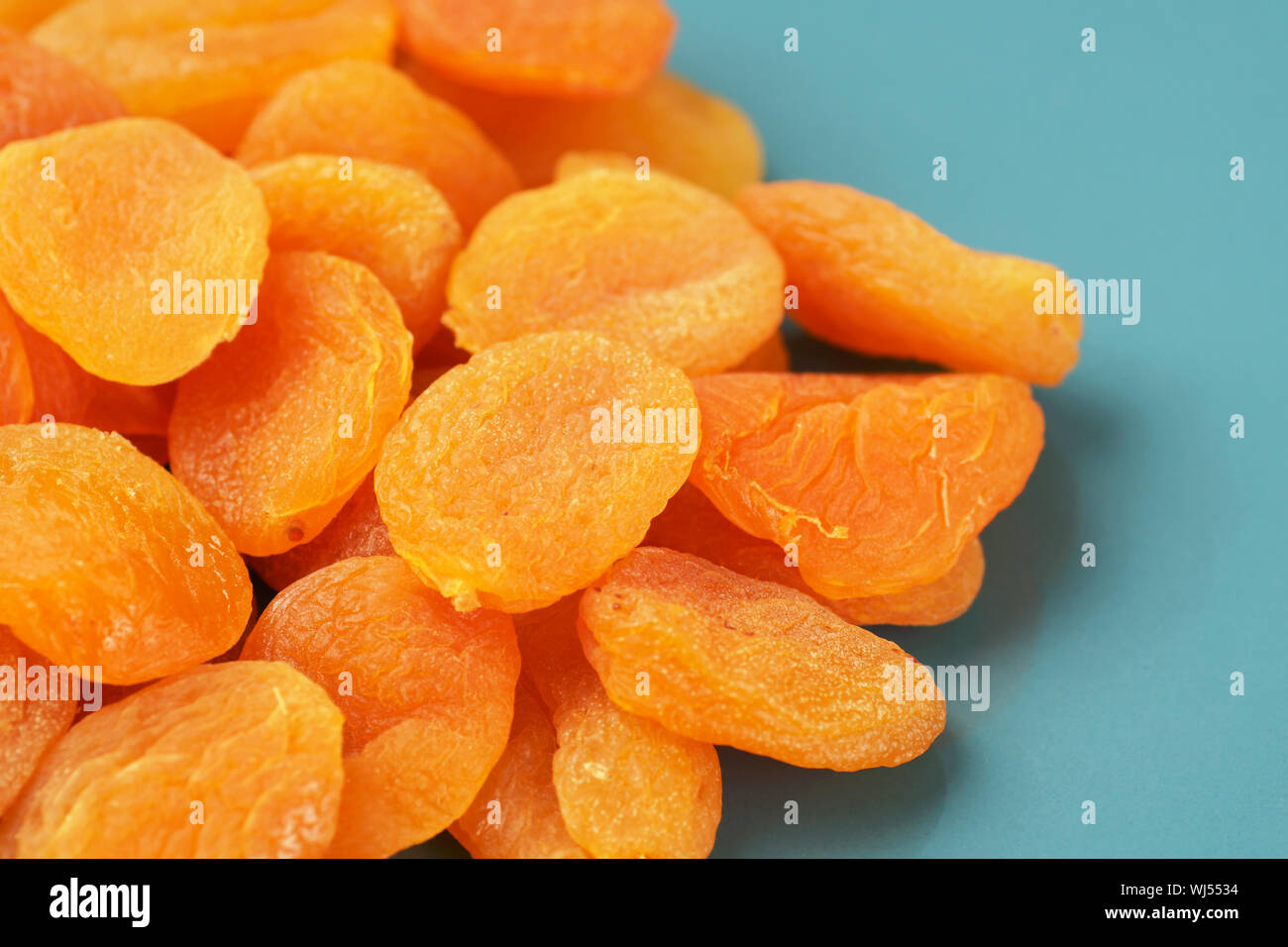 Pile of orange color dried apricots on blue plate, fruit background ...