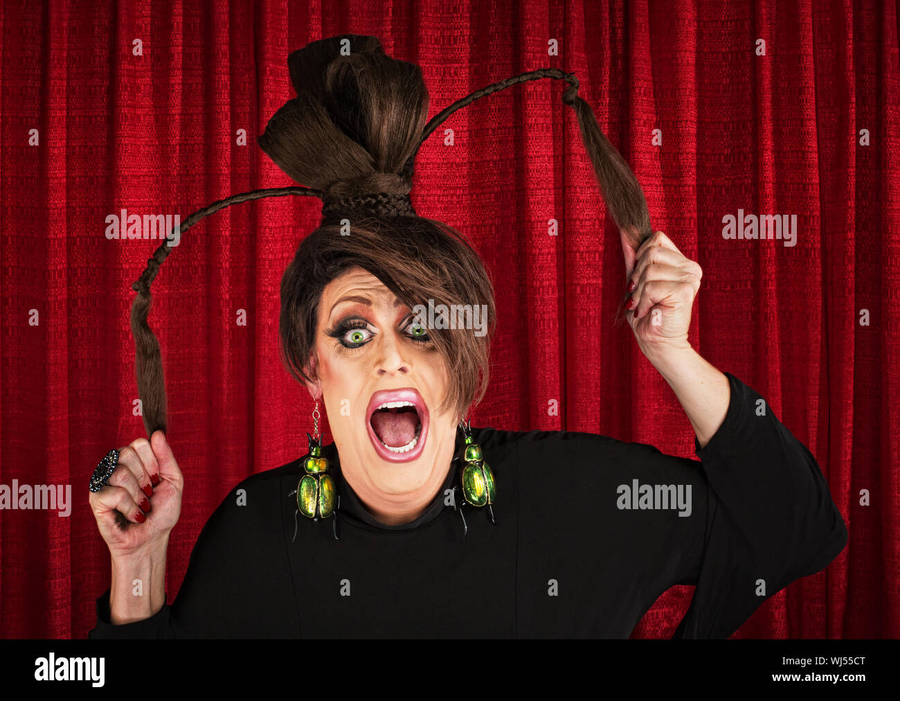 Desperate white drag queen over curtain pulling ponytails Stock Photo ...