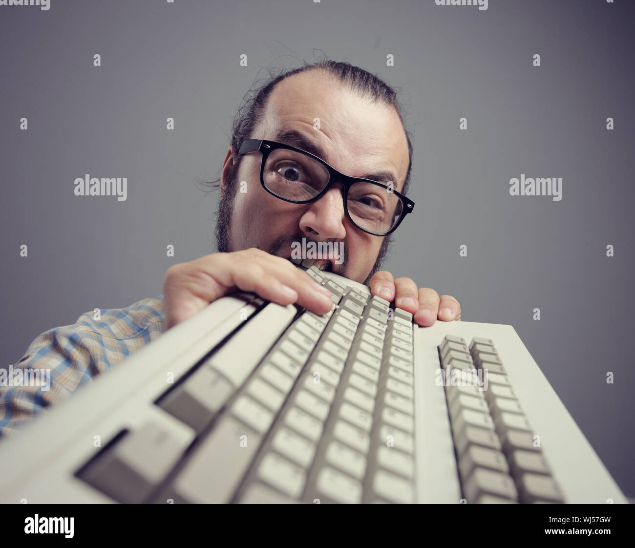 Eccentric angry man bites a keyboard Stock Photo - Alamy