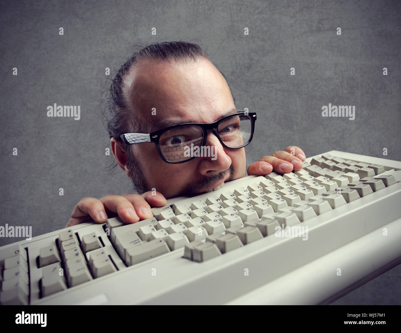 Eccentric angry man bites a keyboard Stock Photo - Alamy