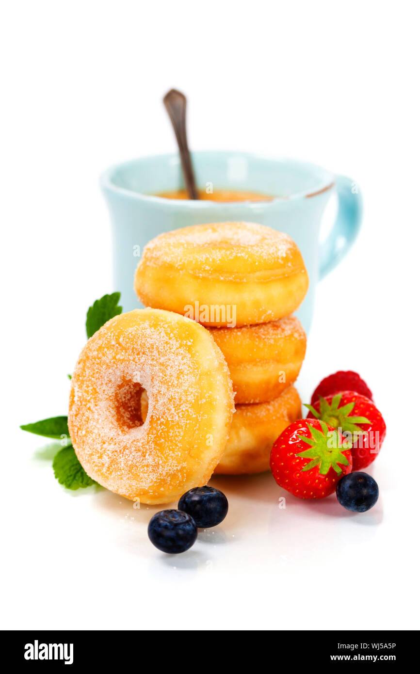 Coffee break with fresh berries and sugary donuts over white background ...
