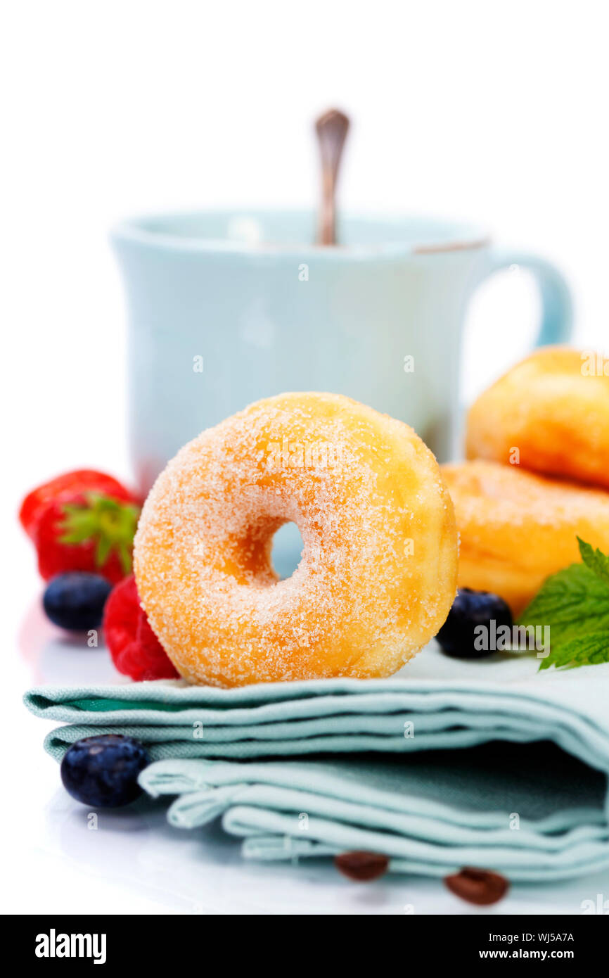 Coffee break with fresh berries and sugary donuts over white background ...