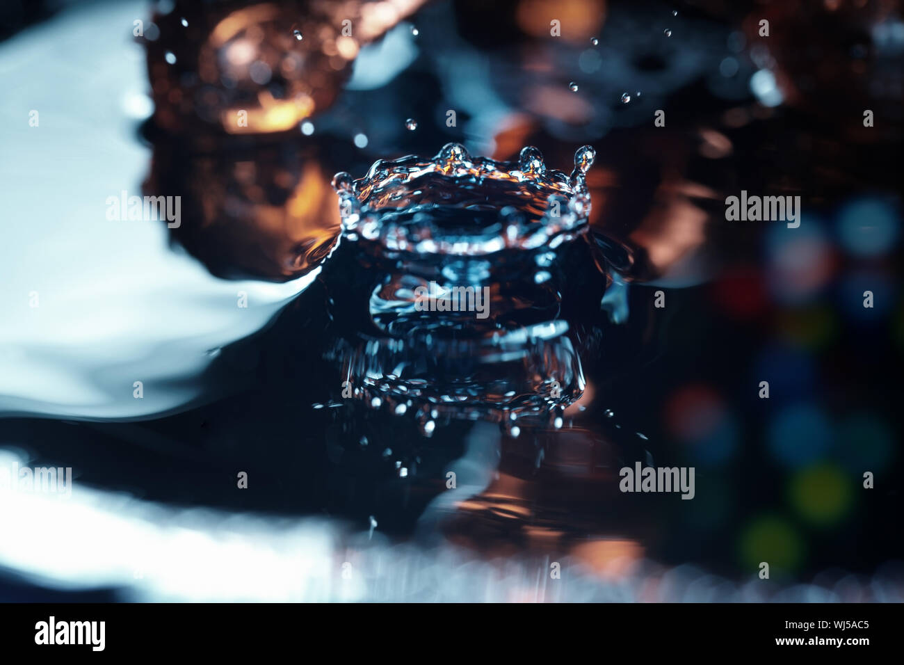 Extremely macro photo of the liquid drop falling on a wet colorful ...