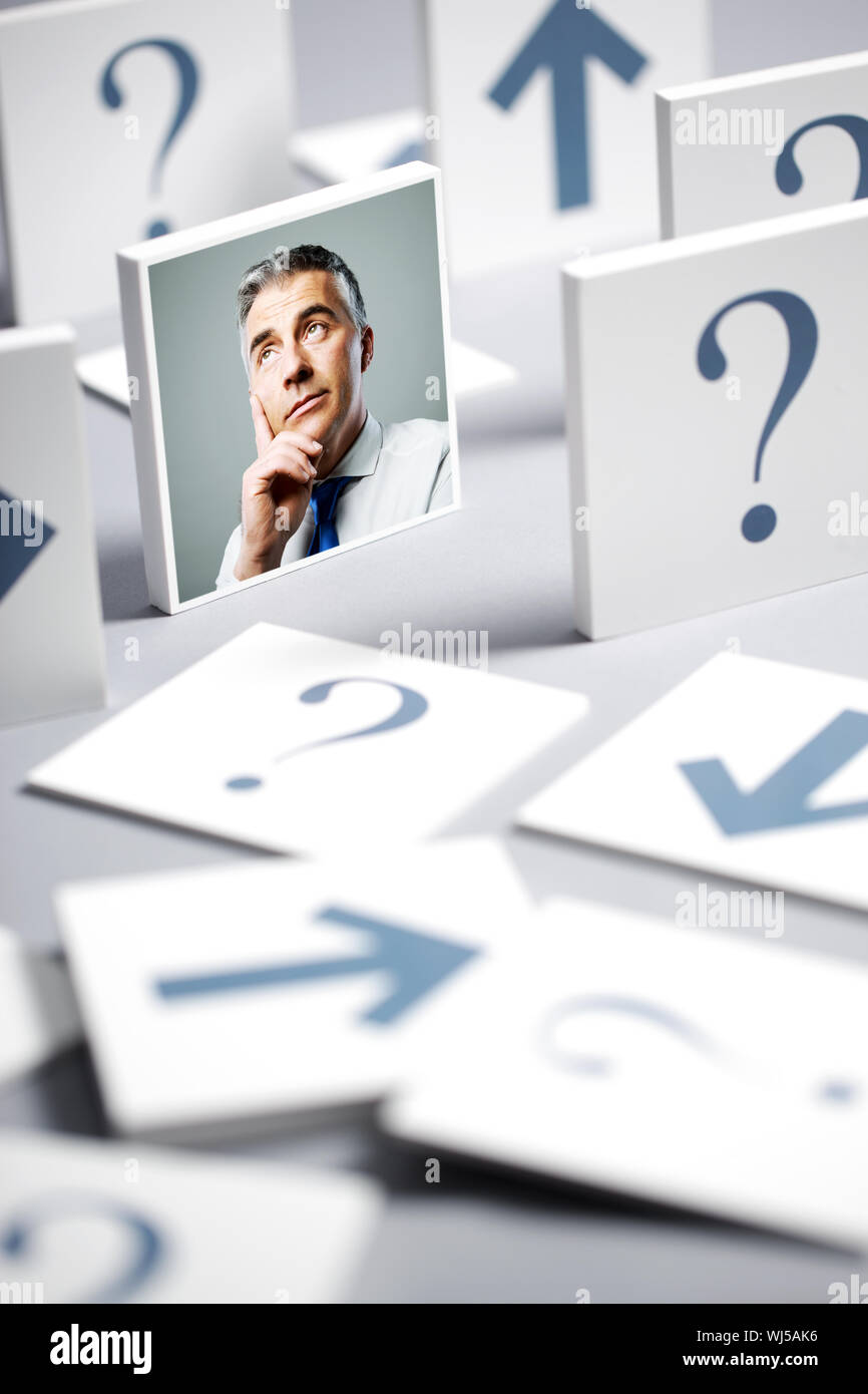 Portrait of a confused businessman surrounded by question marks and ...
