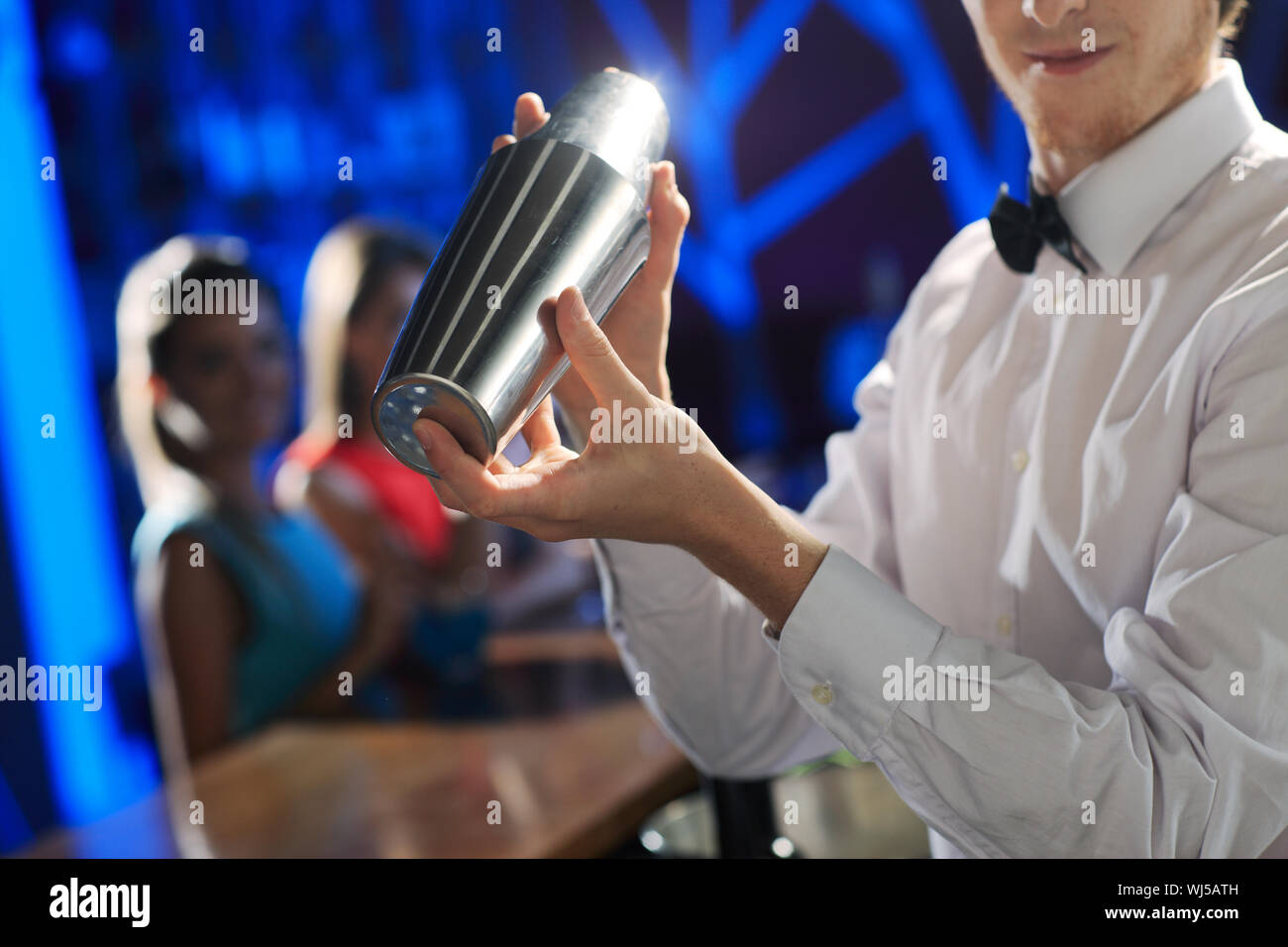 Bartender shaking a cocktail, young women on the background Stock Photo ...
