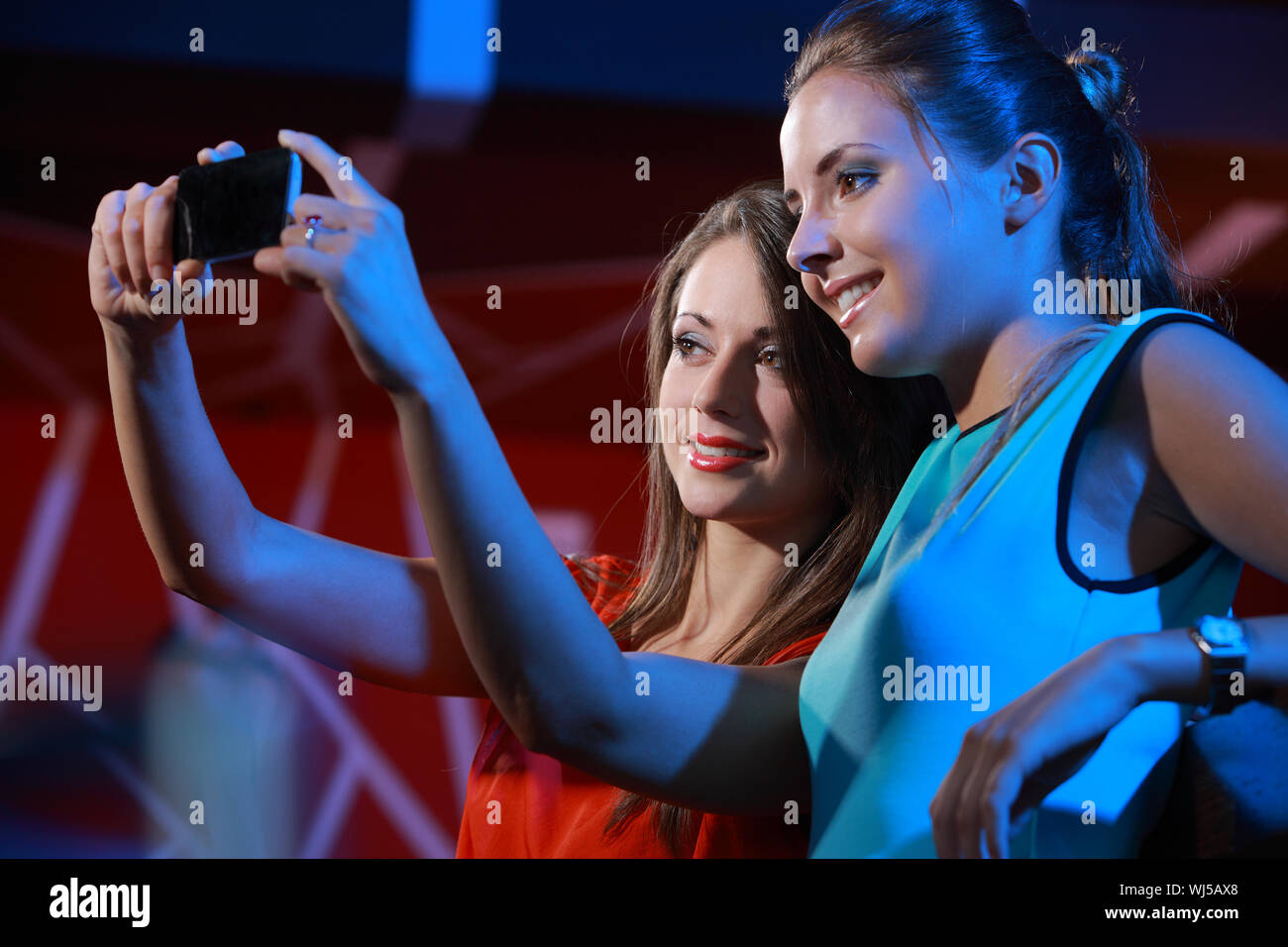 Two happy women at nightclub party taking a self-portrait with ...