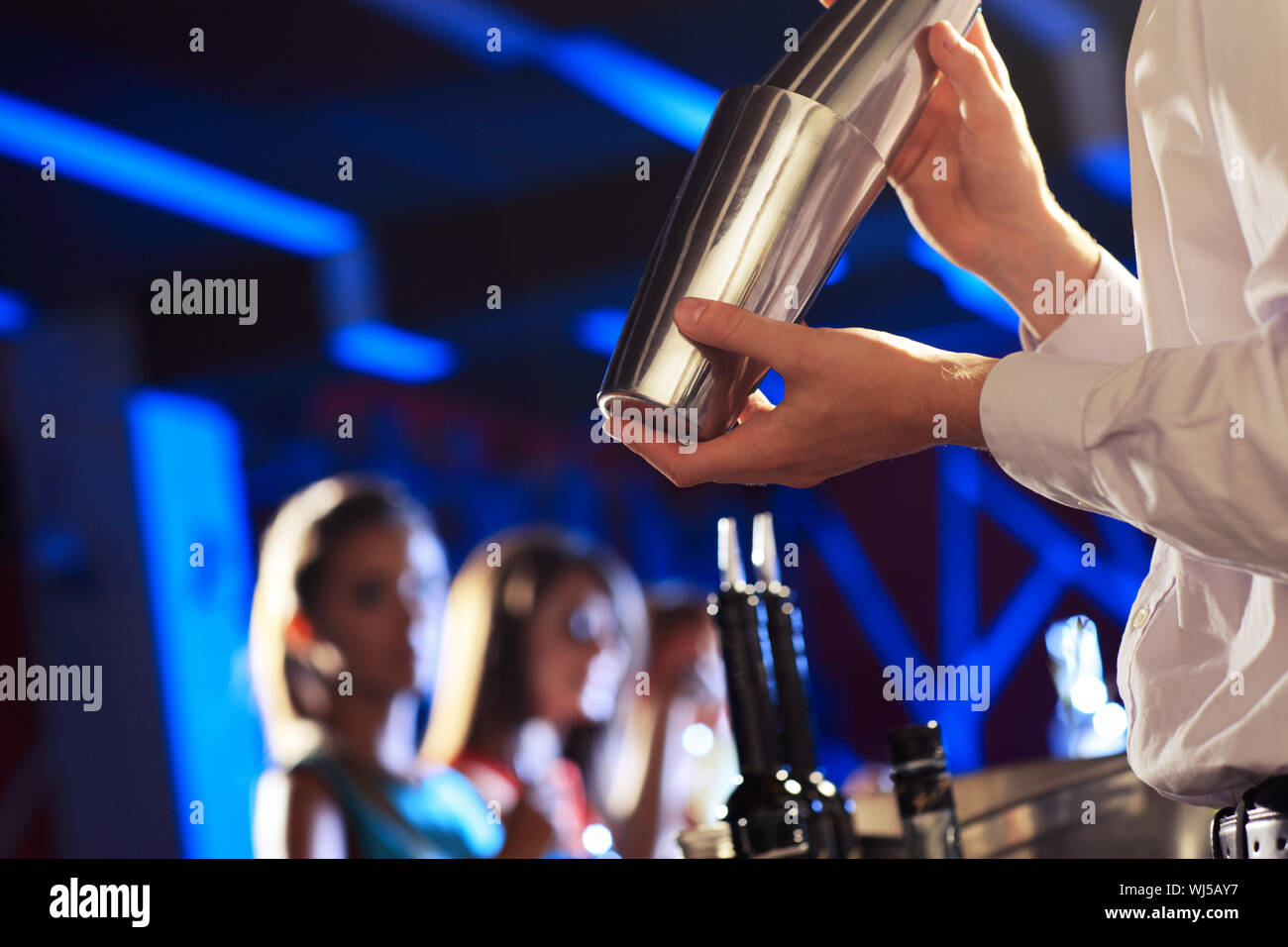 Bartender shaking a cocktail, young women on the background Stock Photo ...